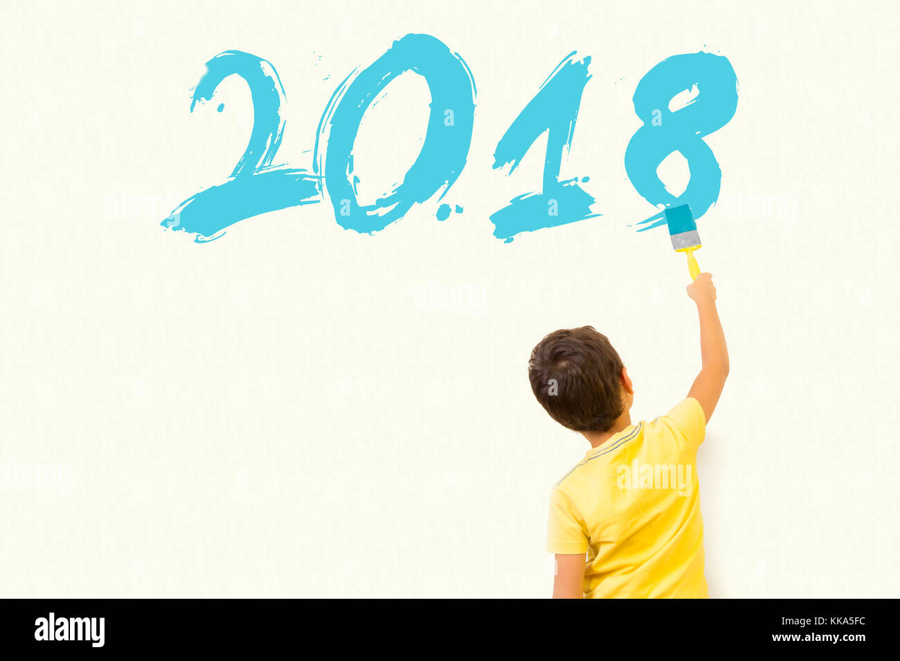 Cute little boy drawing new year 2018 with painting brush on wall ...