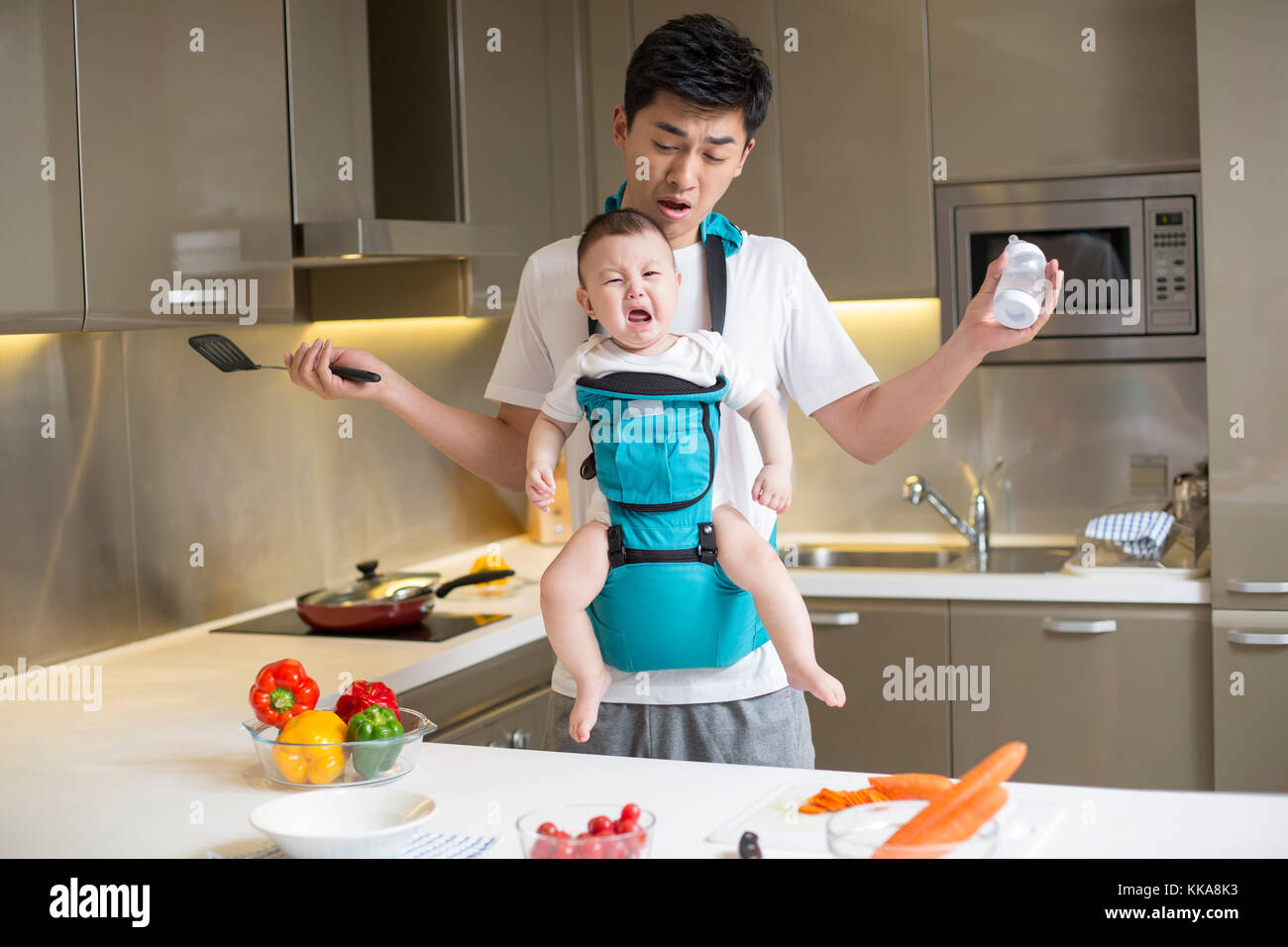 Chinese father holding baby and cooking in the kitchen Stock Photo - Alamy