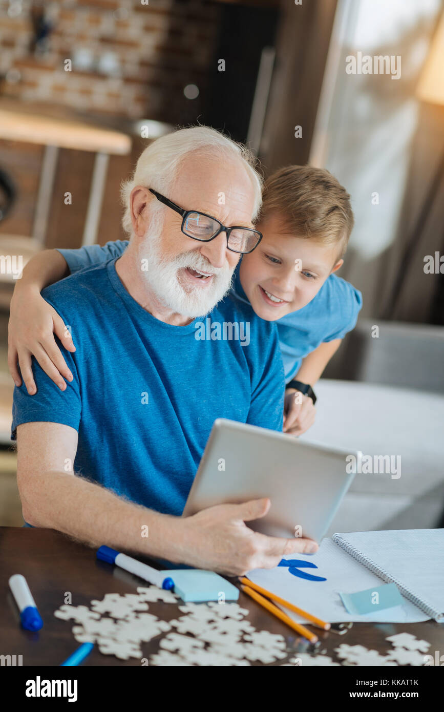 Cheerful positive boy standing behind his grandfather Stock Photo - Alamy