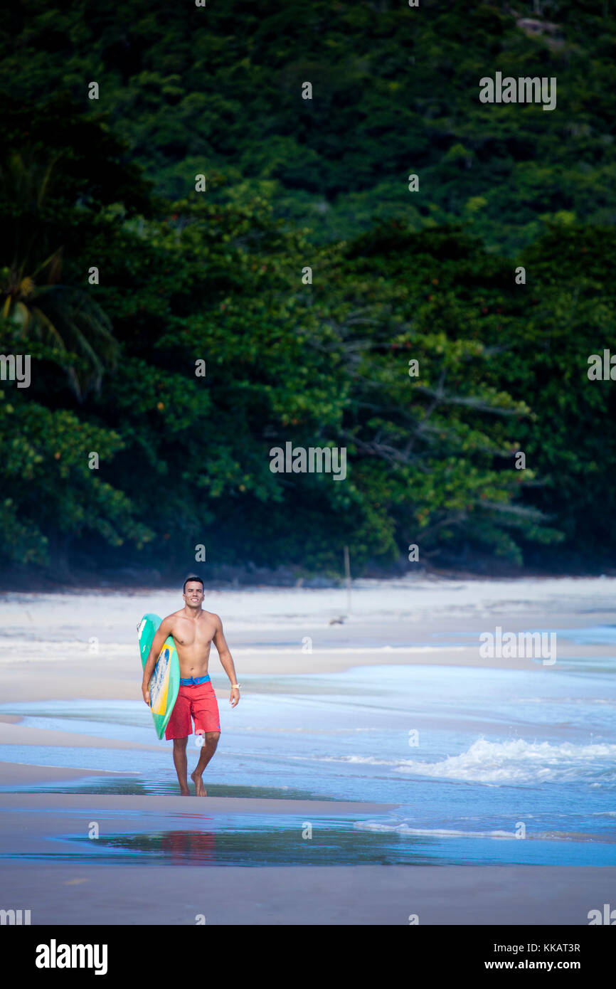 Brazilian male surfer with a Brazilian flag surfboard on a beach in Rio ...