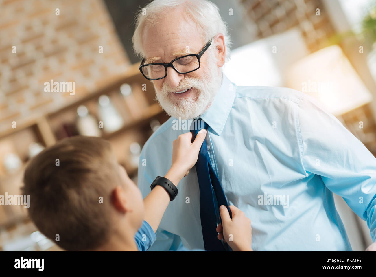 Positive caring boy fixing his grandfathers tie Stock Photo - Alamy