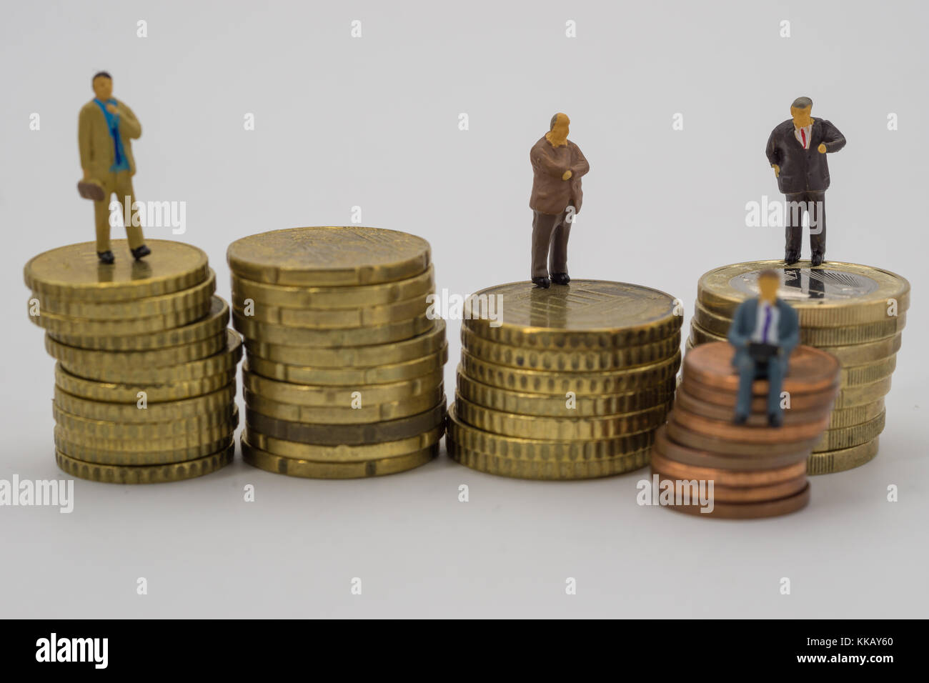 Miniature people sitting on stack coins. Isolated on white background ...