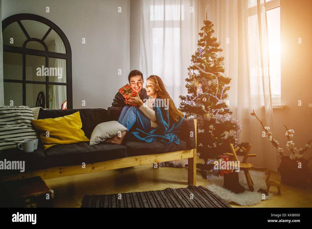 woman open gift box and smiling while her boyfriend sitting close to ...