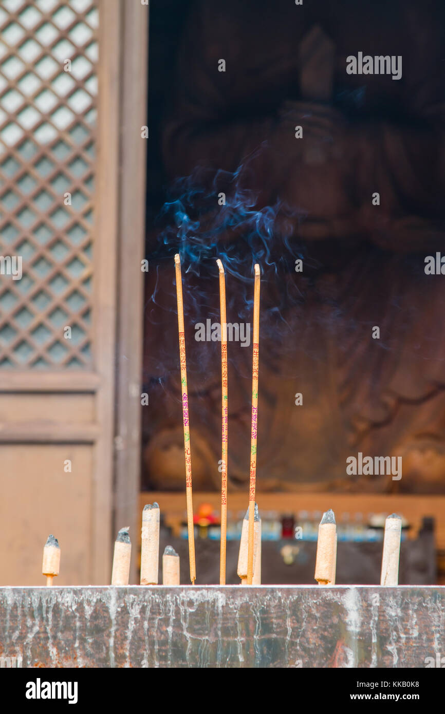 Burning incense at a stone alter in front of a temple housing a giant ...