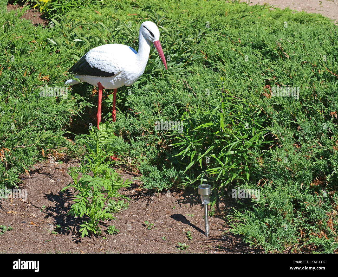 Decorative artificial plastic toy bird stork in flower bed Stock Photo ...