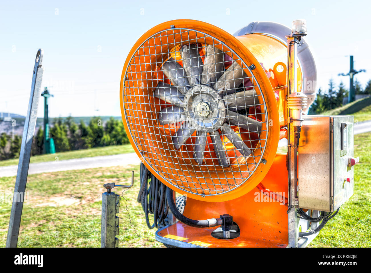 Closeup of orange snow maker machine with fan blades near ski resort ...
