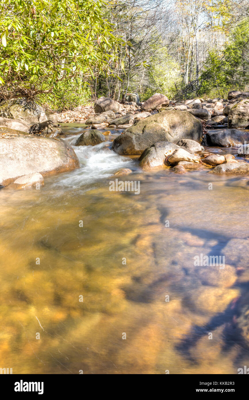 Closeup of shallow rock stream with running water and waterfall in ...
