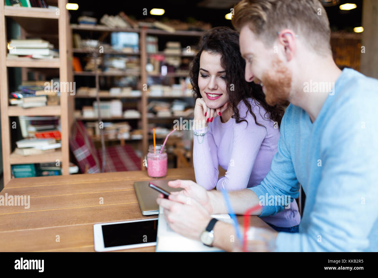 Attractive students learning together in coffee shop Stock Photo - Alamy