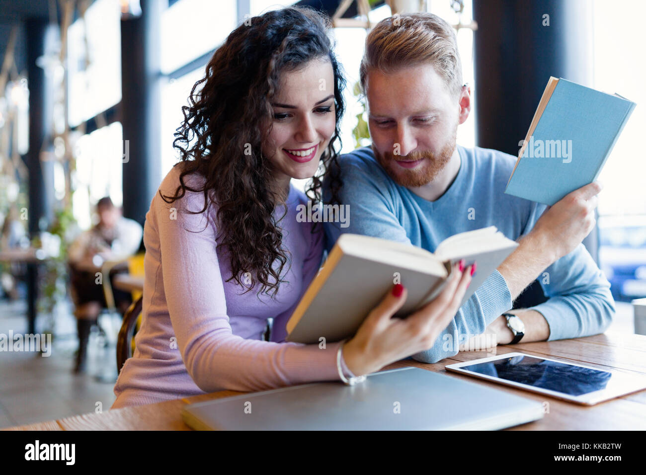 Young couple reading books in coffee shop Stock Photo - Alamy