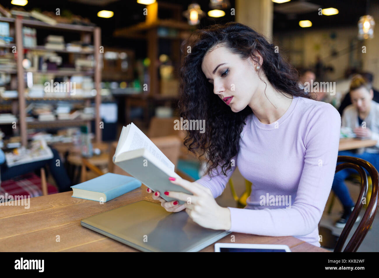 Young pretty girl reading book in coffee shop Stock Photo - Alamy