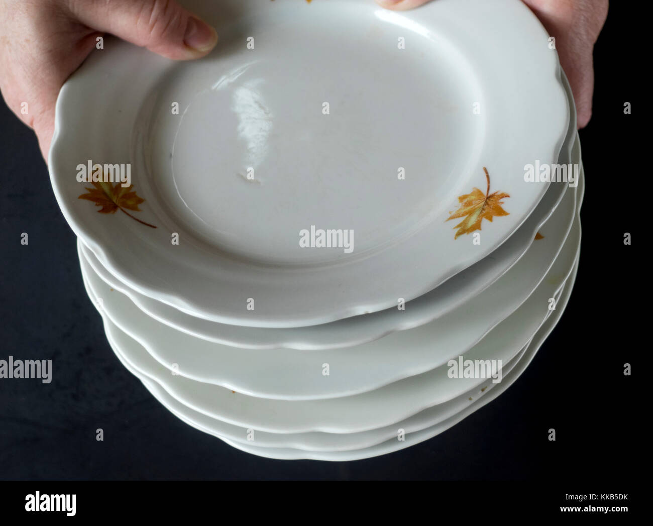 high above view of female hands with a stack of plates on black ...