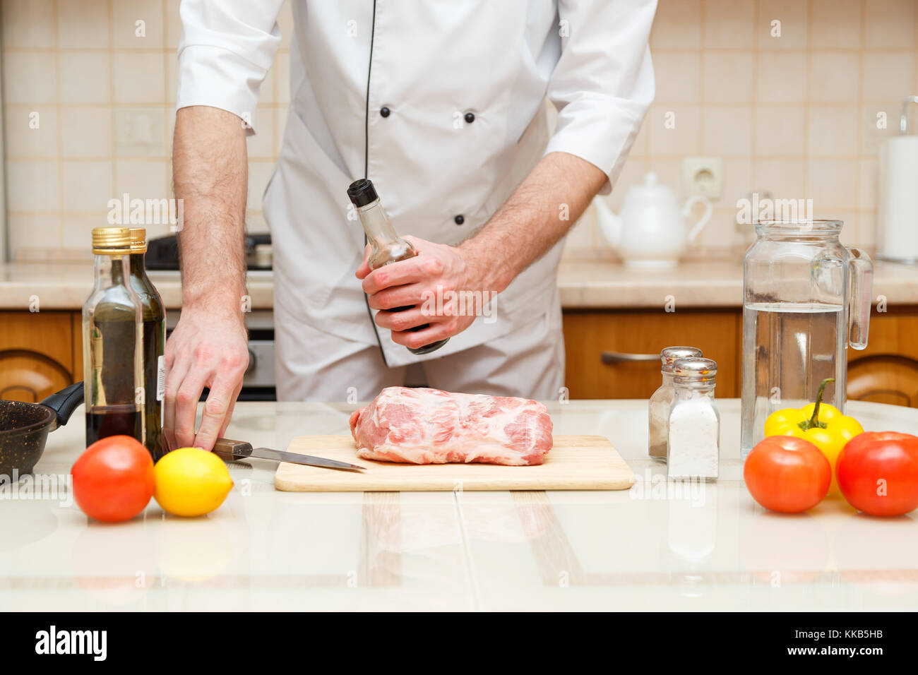 Man's hand holds bottle with souce. Professional cook prepare the meat ...