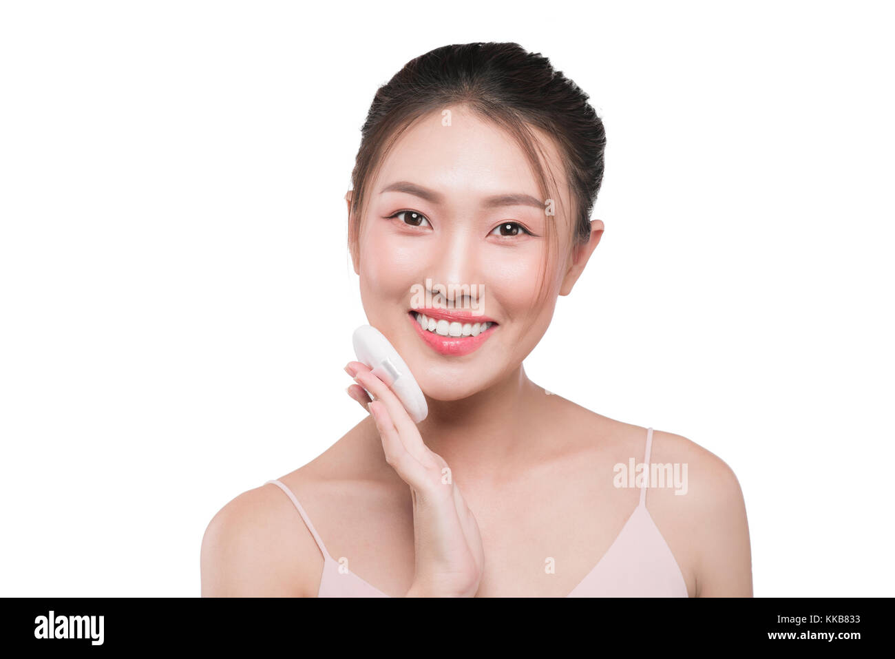 Cute girl with black hair applying powder on her face with powder puff ...