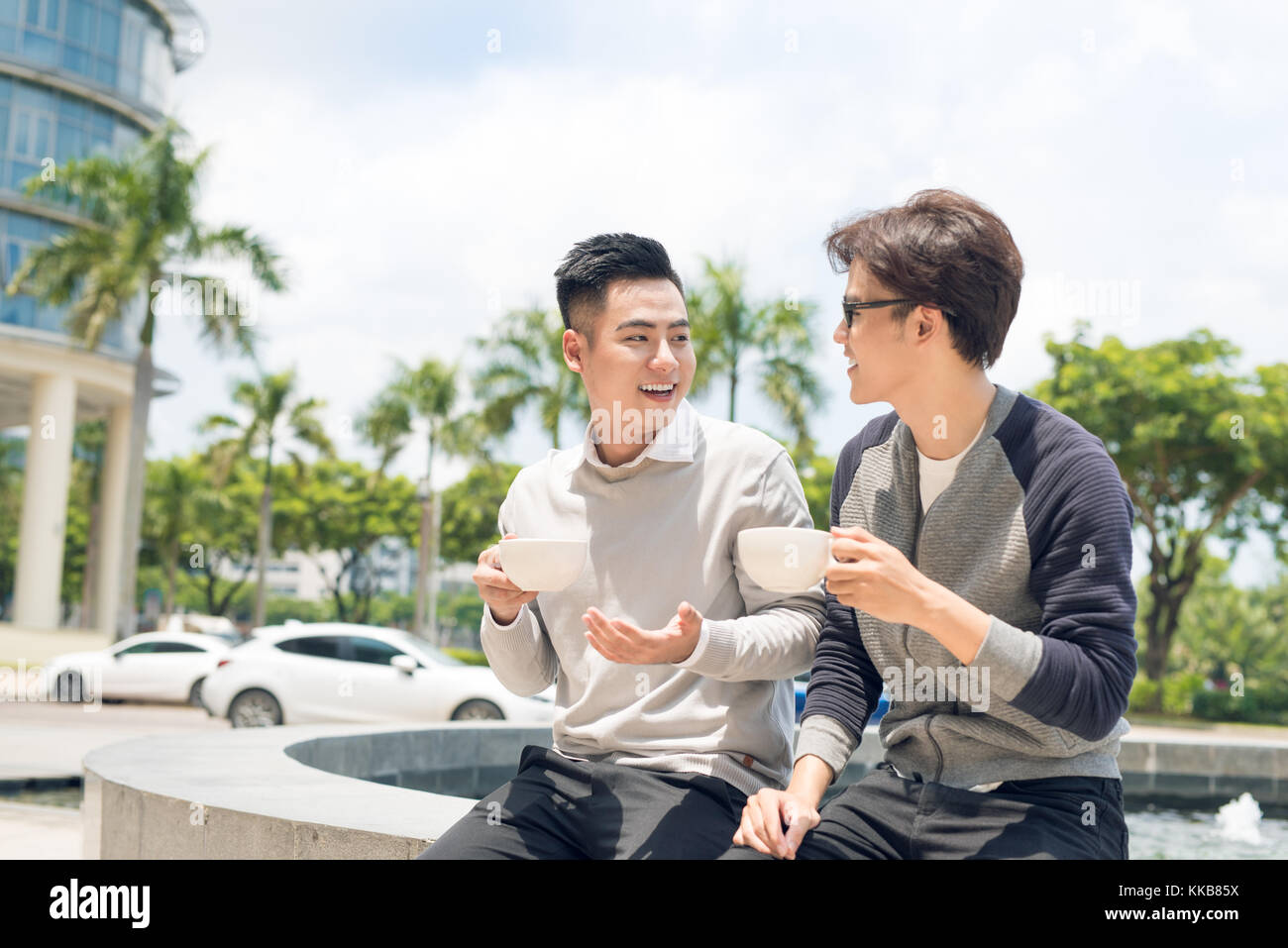Two adult male friends sit talking over coffee outside cafe Stock Photo ...