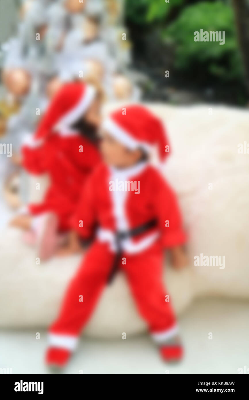 Blurred image of little boy and girl in cute Santa Claus costume with a ...