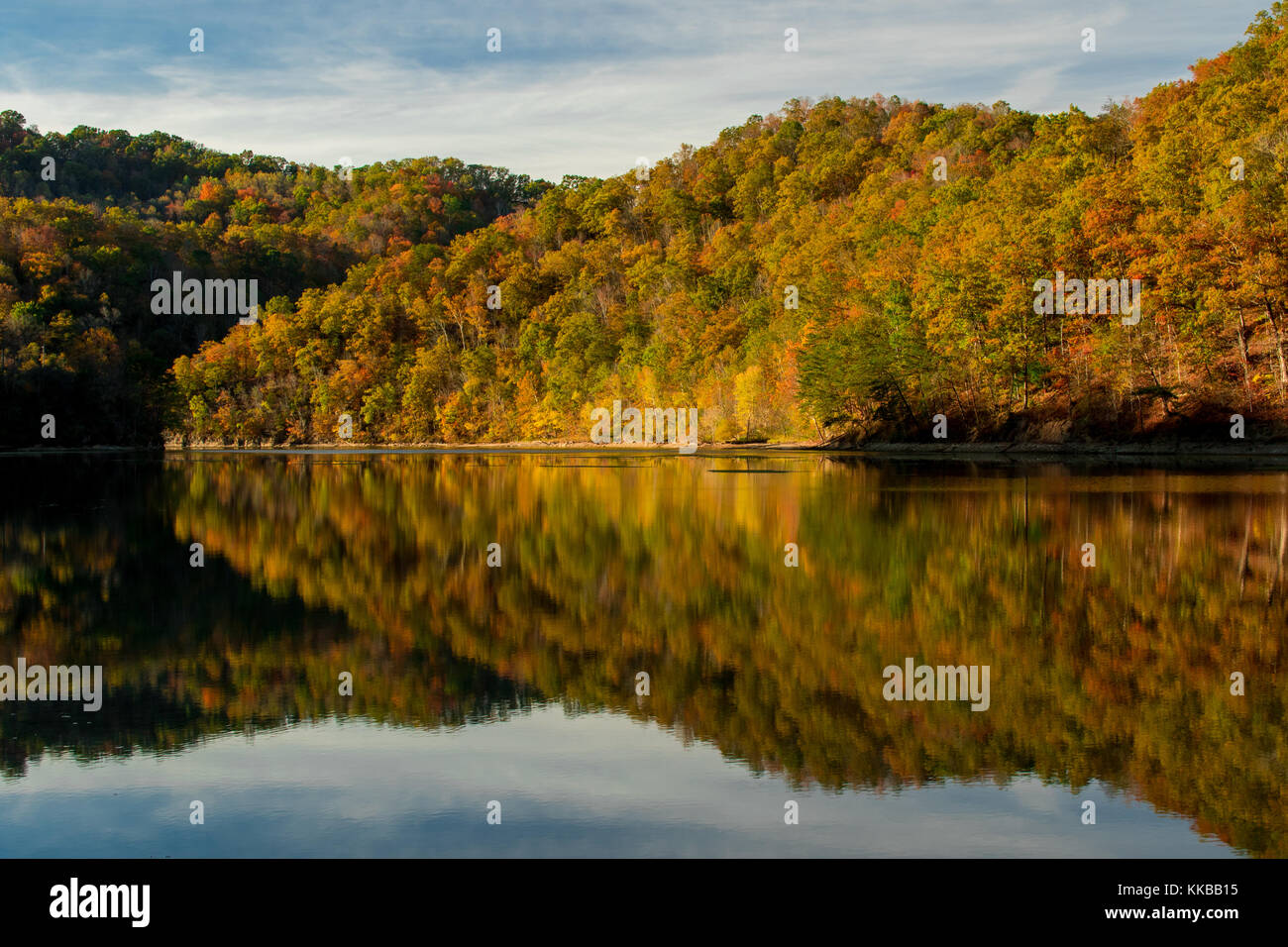 Still lake water reflects a the colors of autumn from the hillside ...