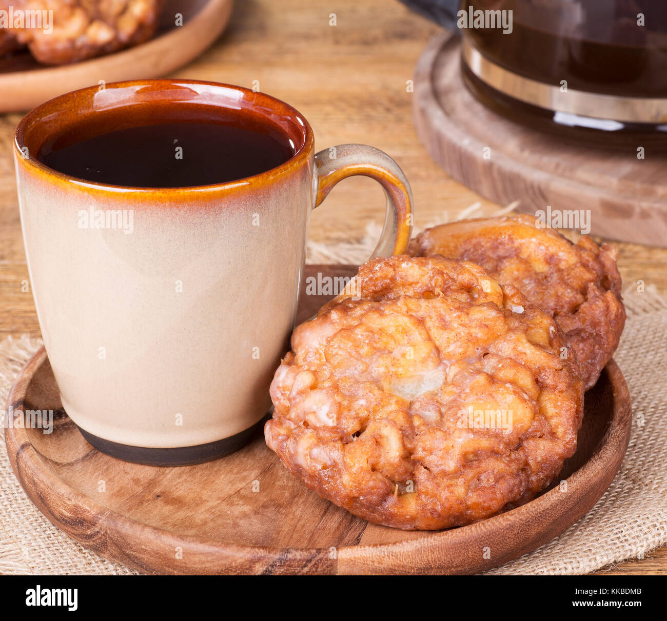 Glazed apple fritters and cup of coffee on a wooden plate Stock Photo ...