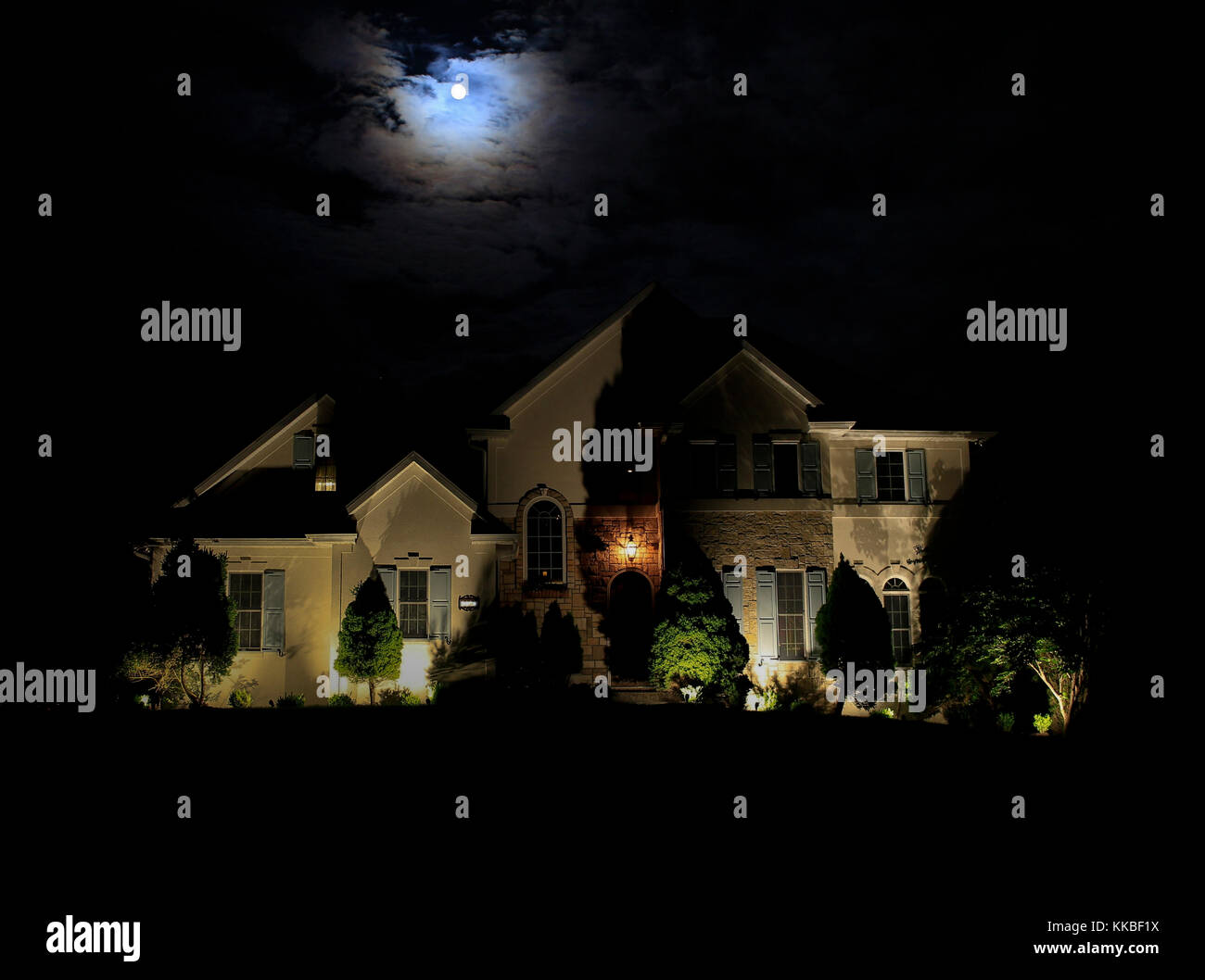 House lit by the moon; moon behind the clouds above the roof Stock ...