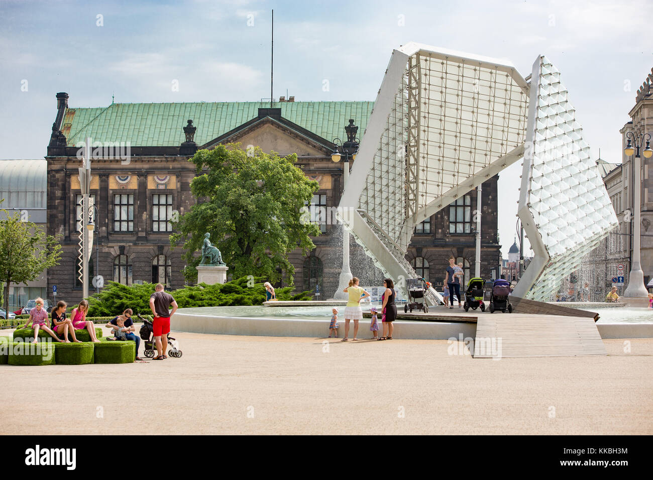 Poland, Poznan: People having a chat and resting by the modern fountain ...