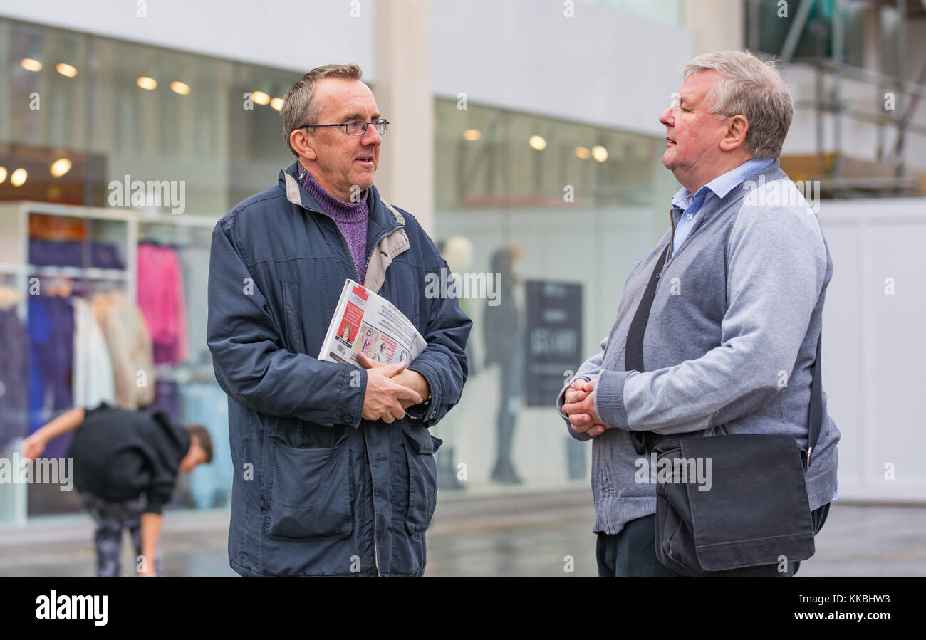 Middle aged men meet in the street and stop to chat, in the UK Stock ...