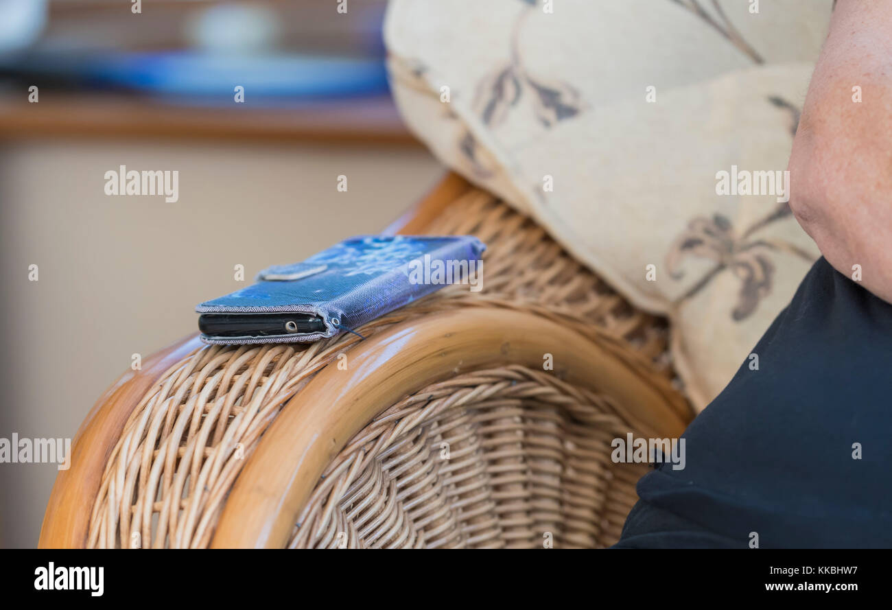 A mobile phone left on the arm of a chair not being used while in a ...