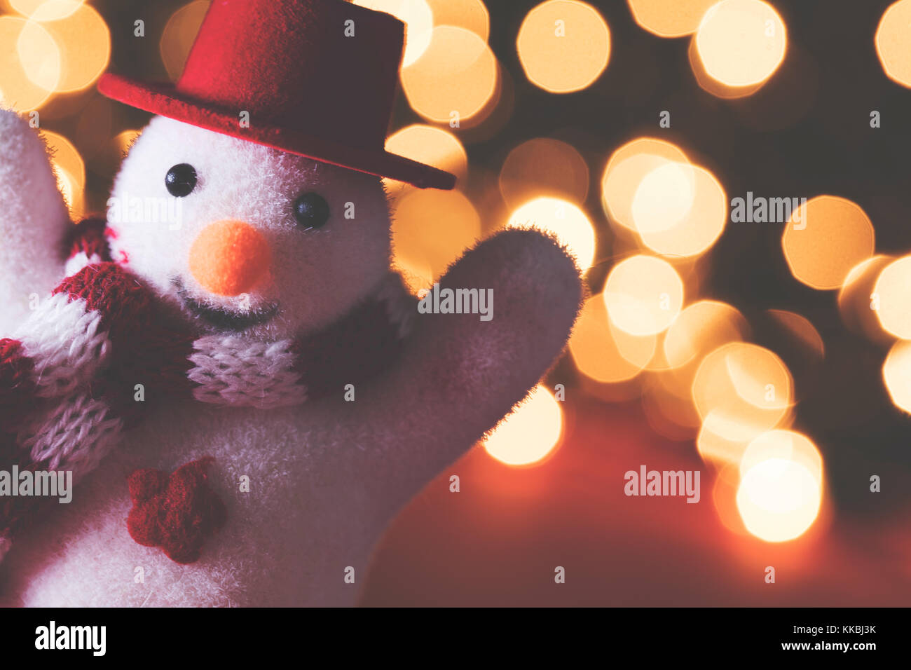 Festive snowman with hat and scarf against blurred bokeh fairy lights ...