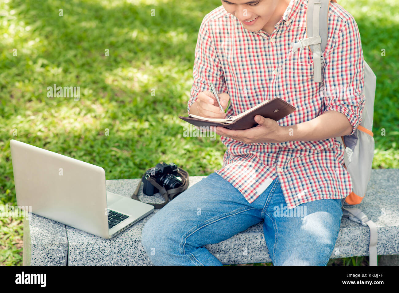 Young asian man with backpack reading a book Stock Photo - Alamy