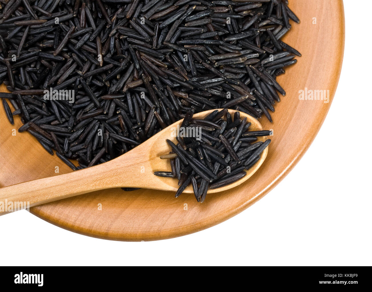wooden plate with grains of black rice on a white background with ...