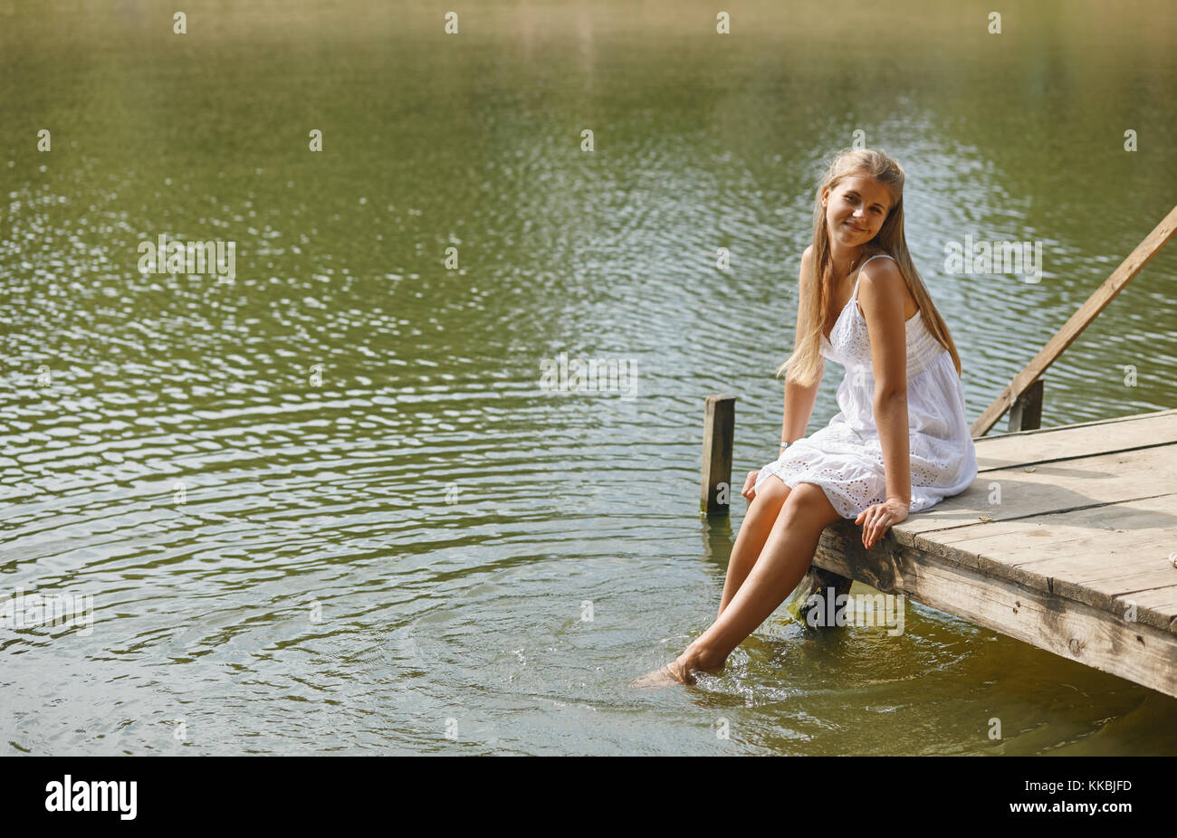 Girl sitting on pier and looking at the river Stock Photo - Alamy