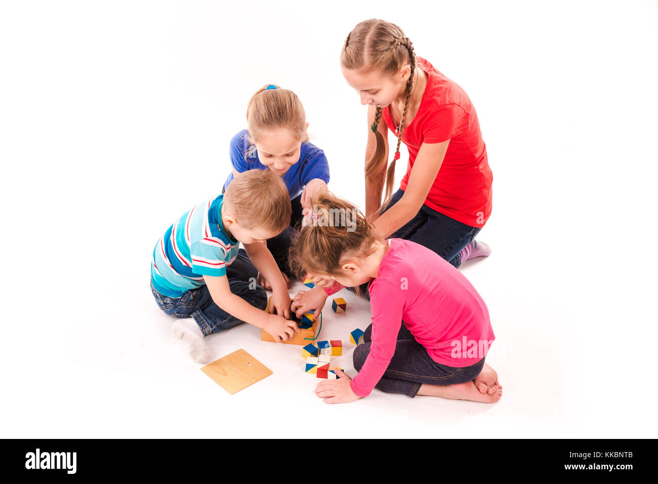 Happy kids playing with building blocks isolated on white. Team work ...