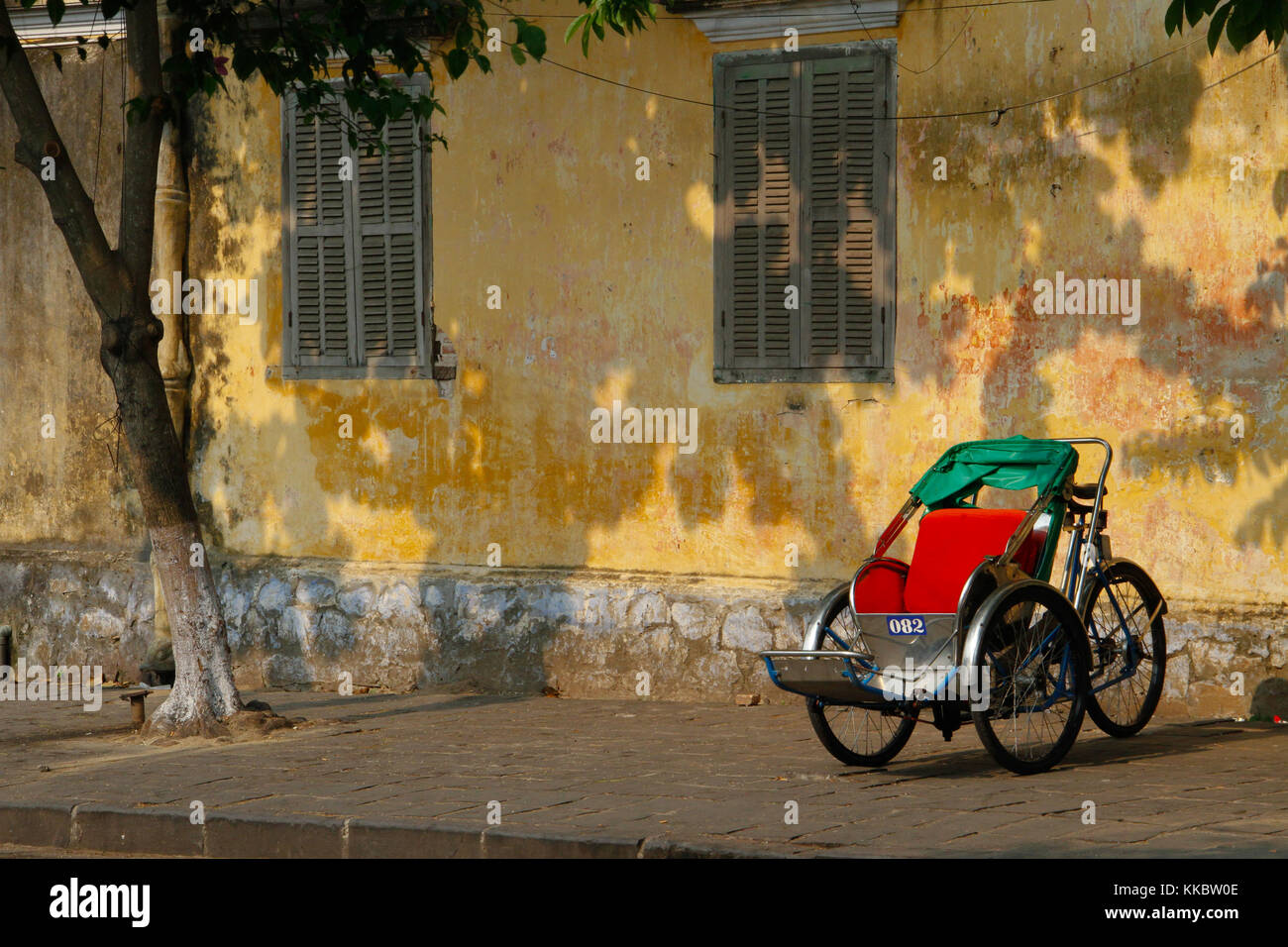 Rickshaw sitting in front of yellow coloured building in late afternoon ...