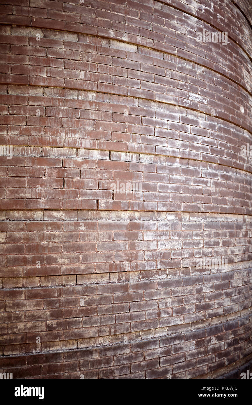 Old vintage curved red brick wall with remnants of whitener in a full ...