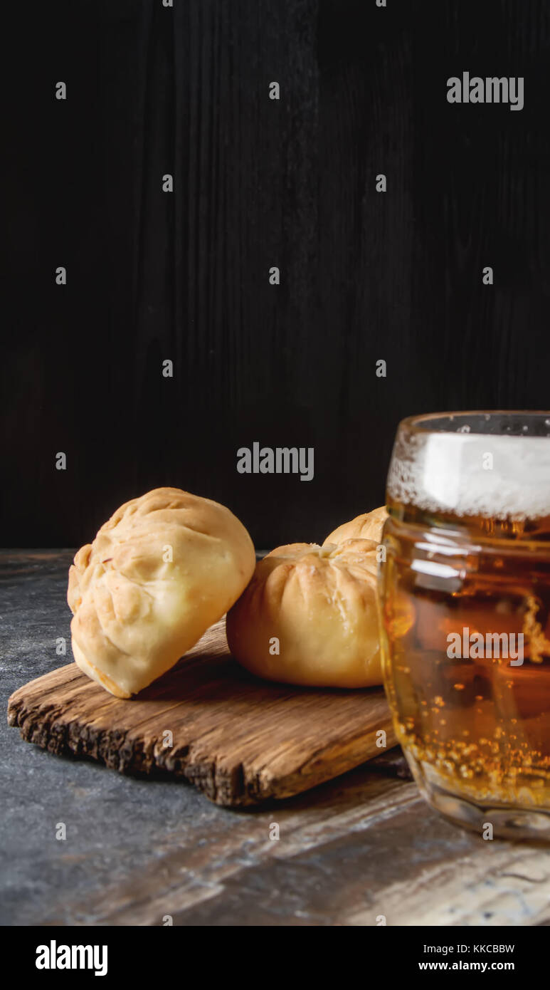 Traditional Russian meat pie, (belyashi) with beer. Dark background ...