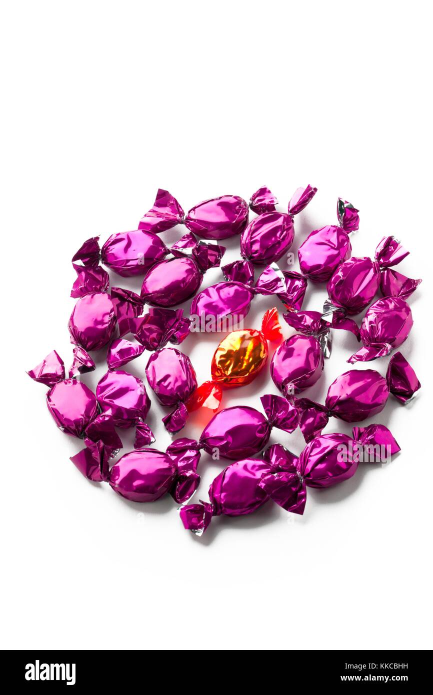 view of a one golden candy in between of purple candies Stock Photo - Alamy