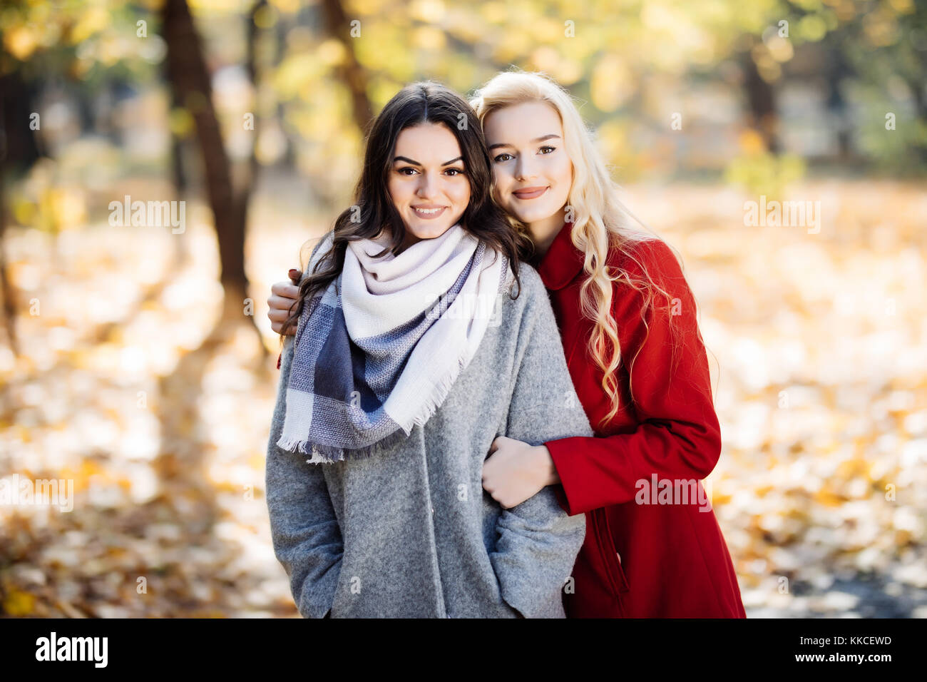Full length portrait of a young woman to her girlfriend in autumn park ...
