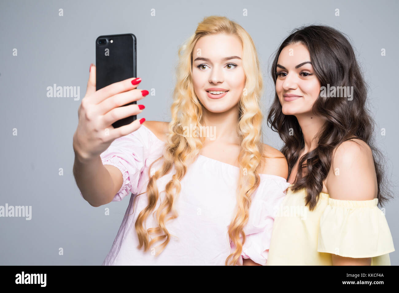 Portrait Of A Happy Two Smiling Girls Making Selfie Photo On Smartphone