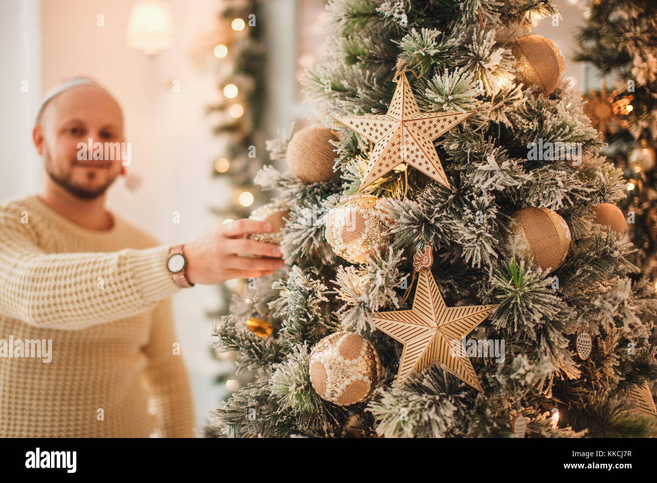 Happy man decorating the Christmas tree at home Stock Photo - Alamy