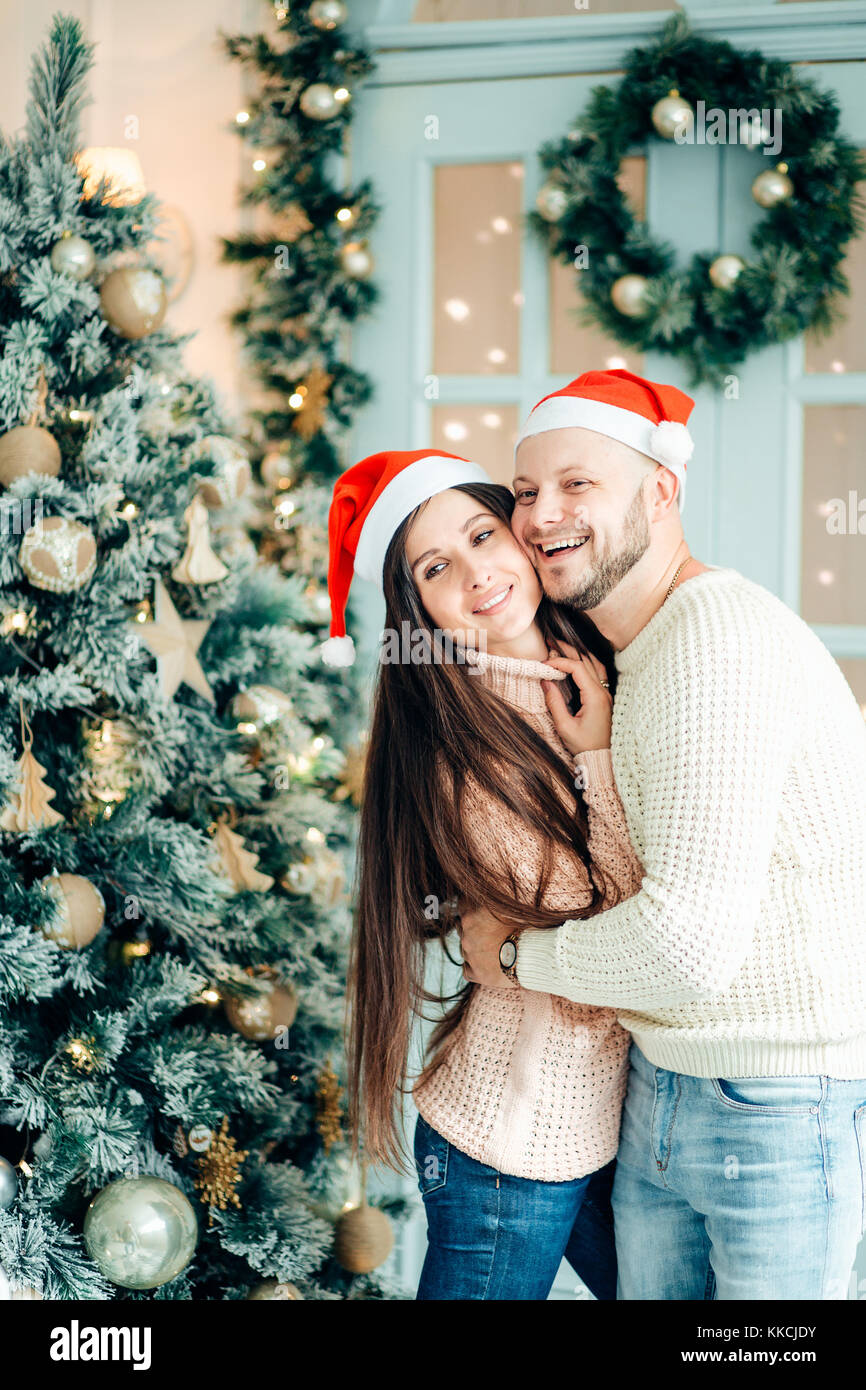 happy couple on Christmas day standing in front of the decorated tree ...
