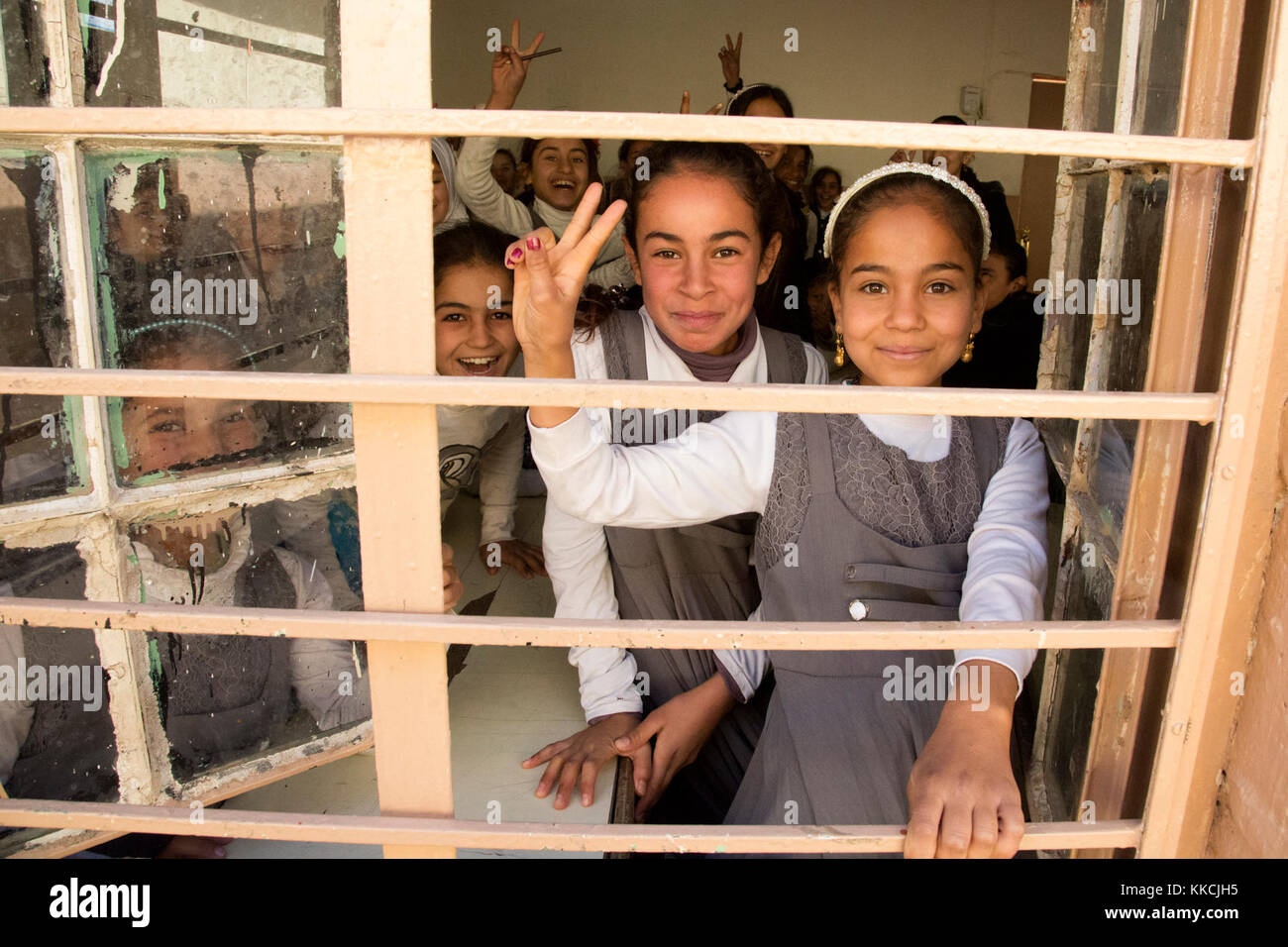 Iraqi students pose for a photo through a school window at a primary ...