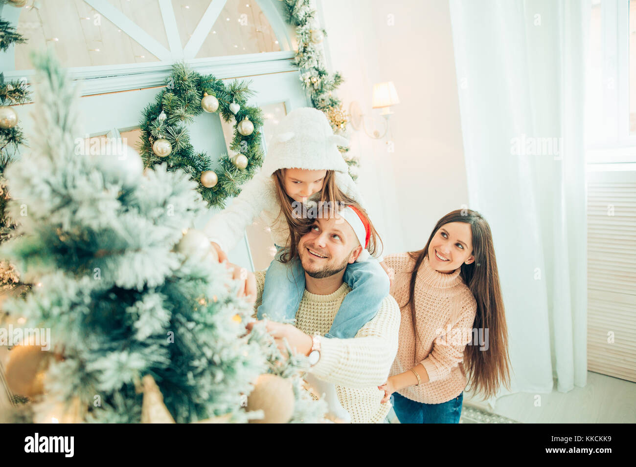 Family decorating a Christmas tree Stock Photo - Alamy