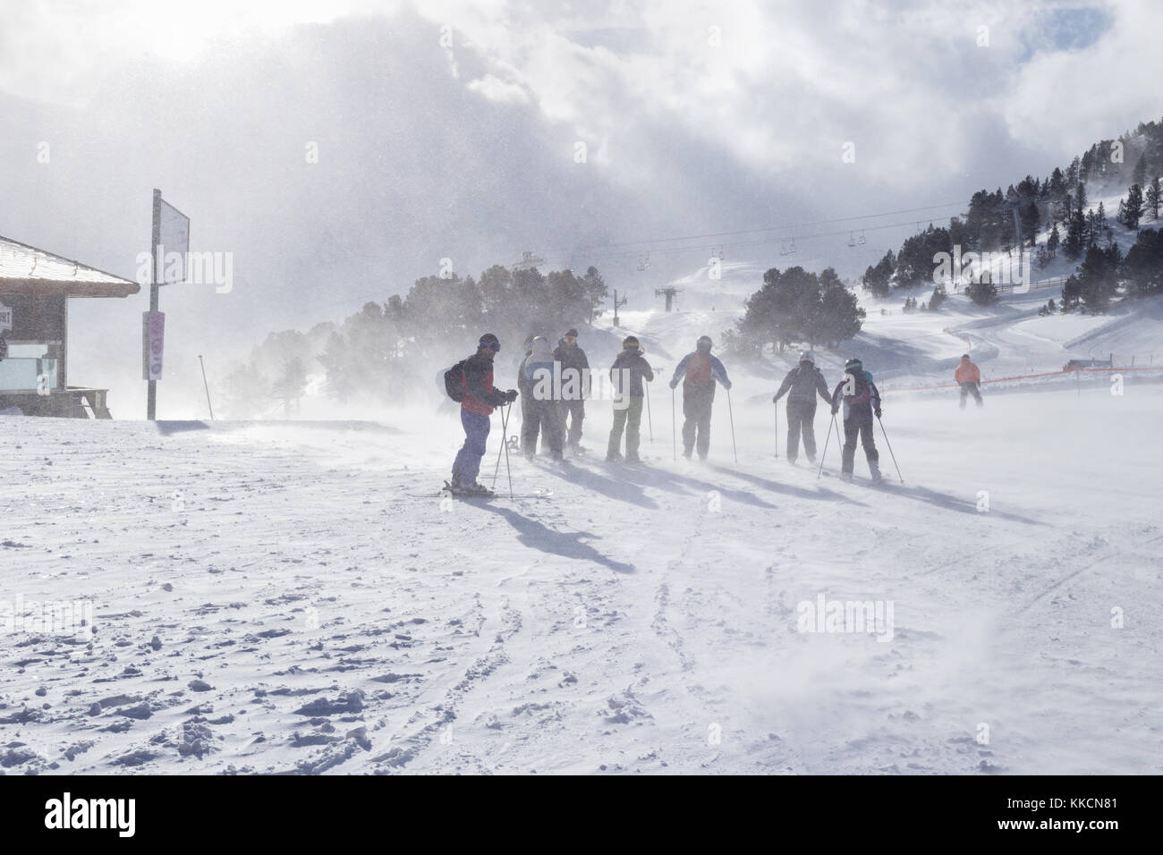Group of mountain skiers during strong wind and a snowstorm. Winter day ...