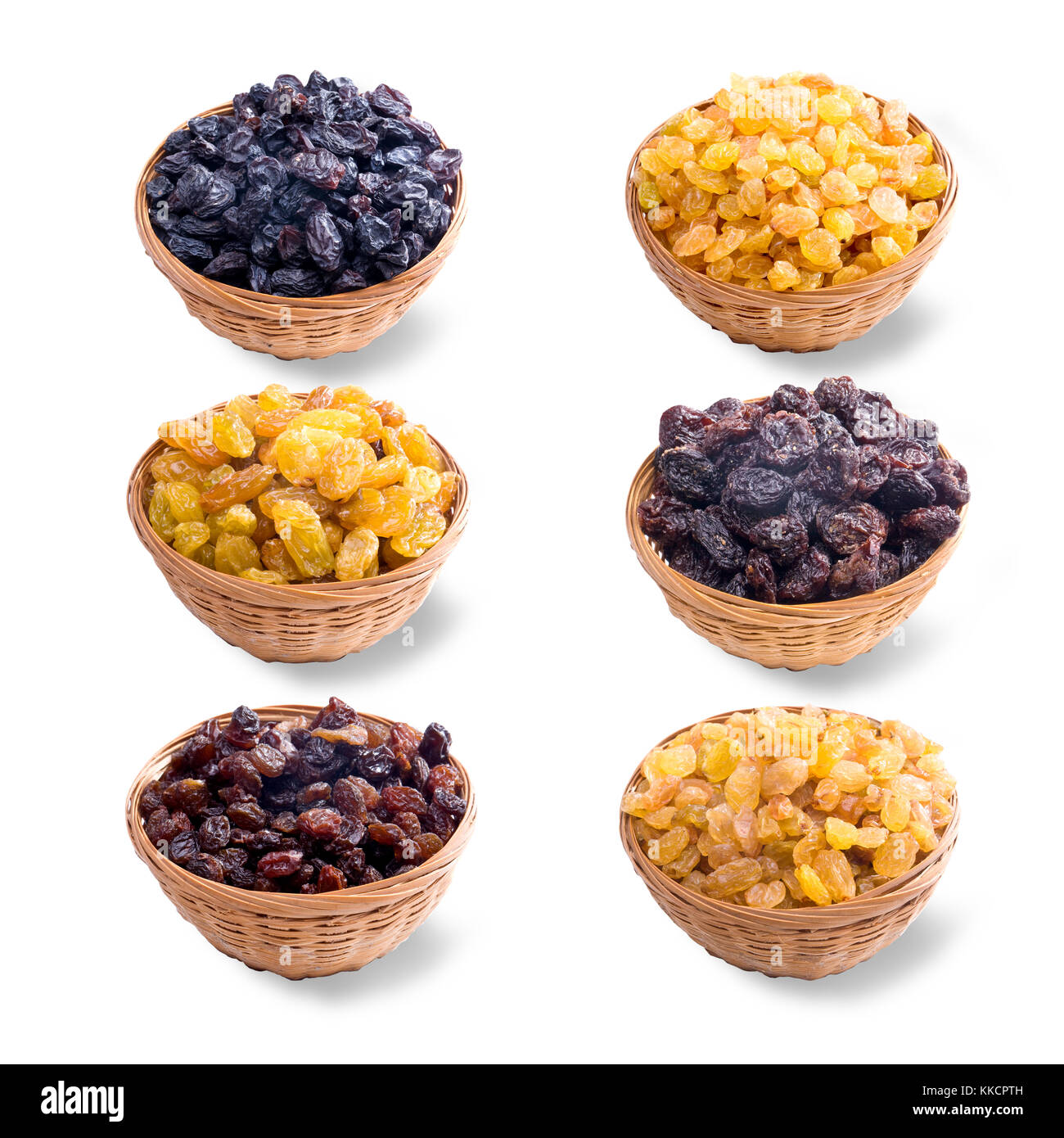 different varieties of raisins in a straw plate on white background ...