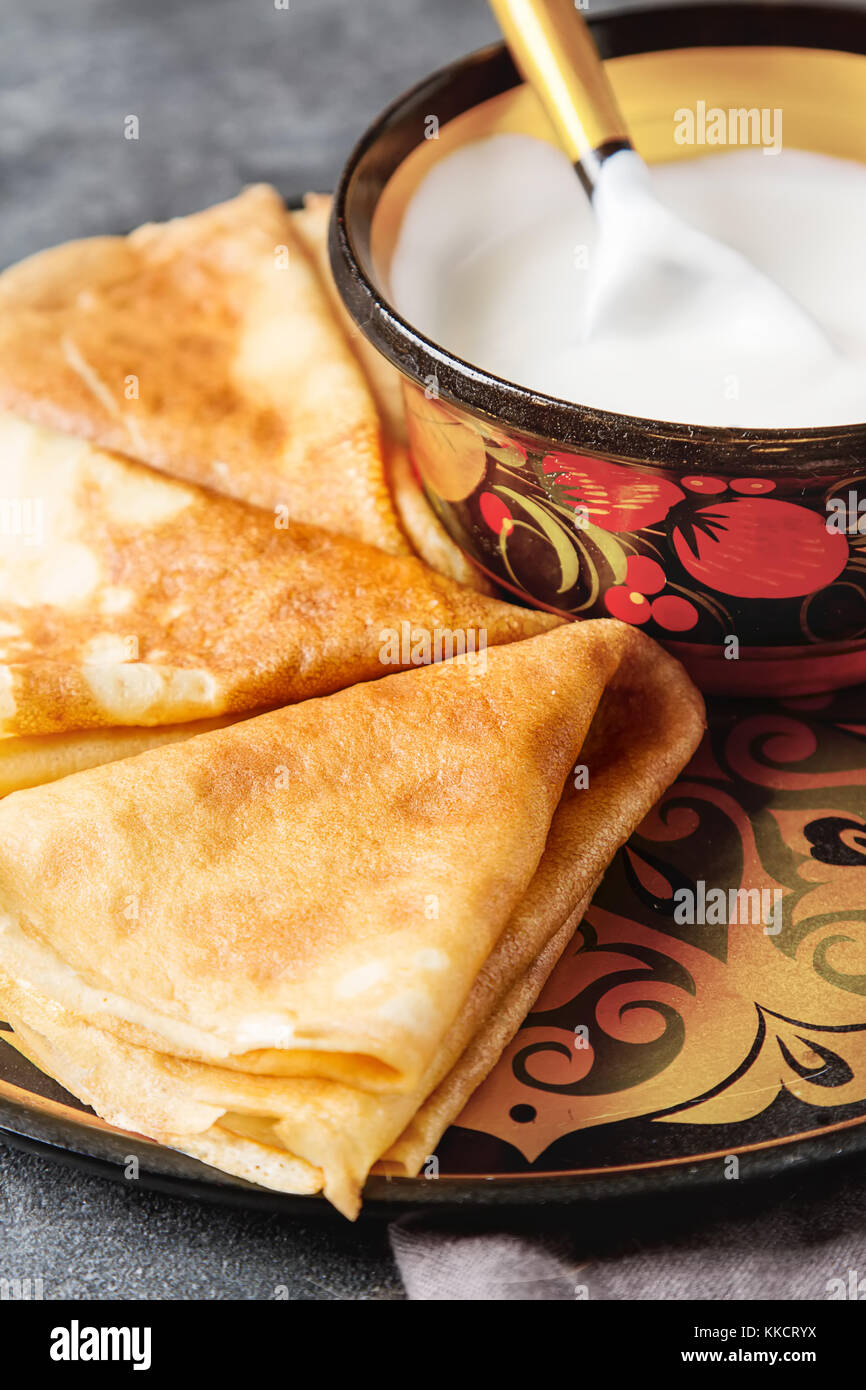 Stack of pancakes on a plate with sour cream. Traditional for the ...