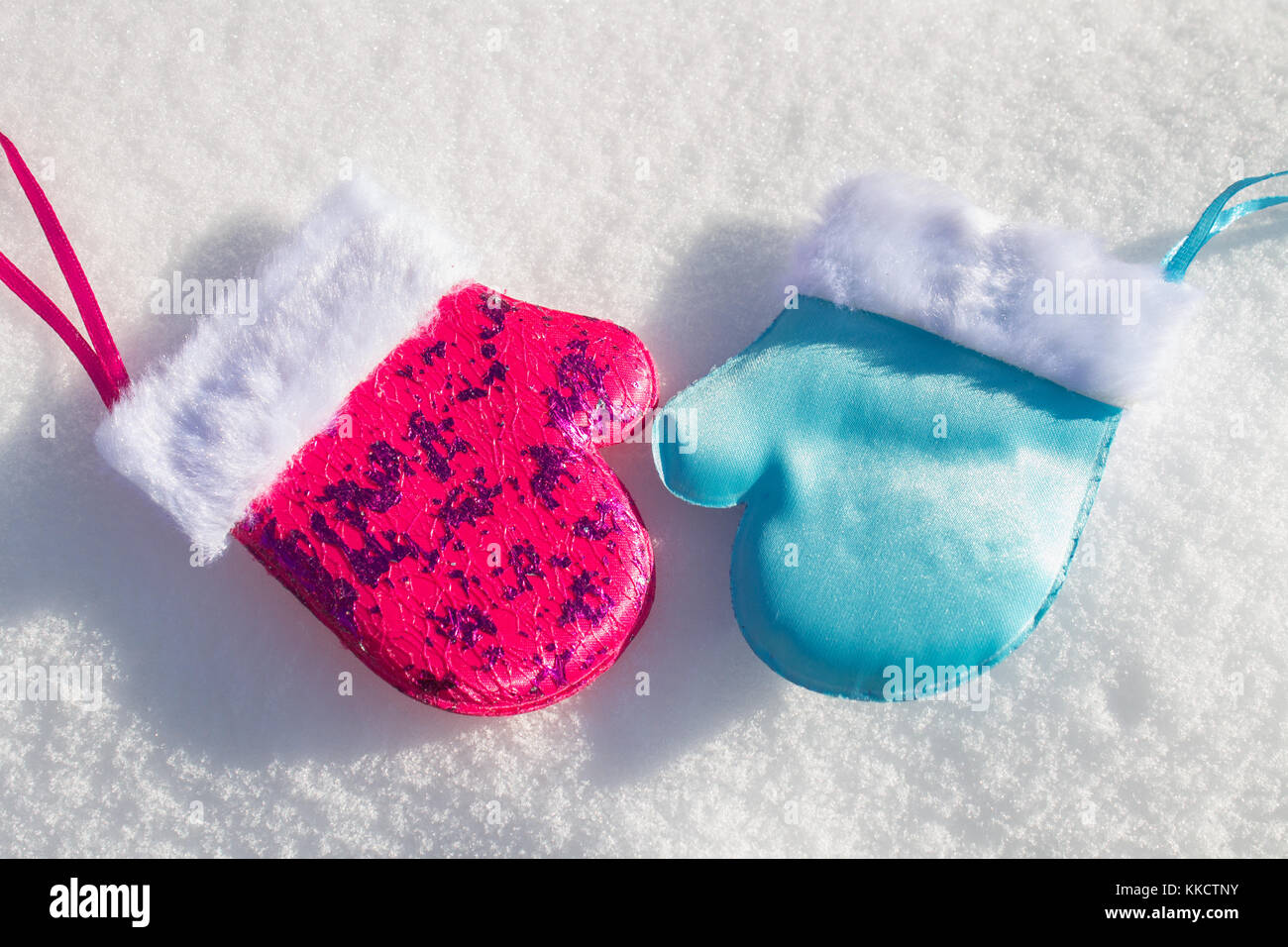 Blue and pink mittens on the snow in an embrace. Christmas toys. Male ...