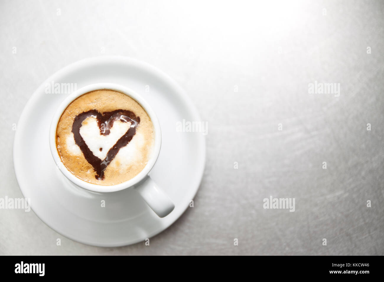 Cup of coffee with a shape of heart made with liquid chocolate on top ...