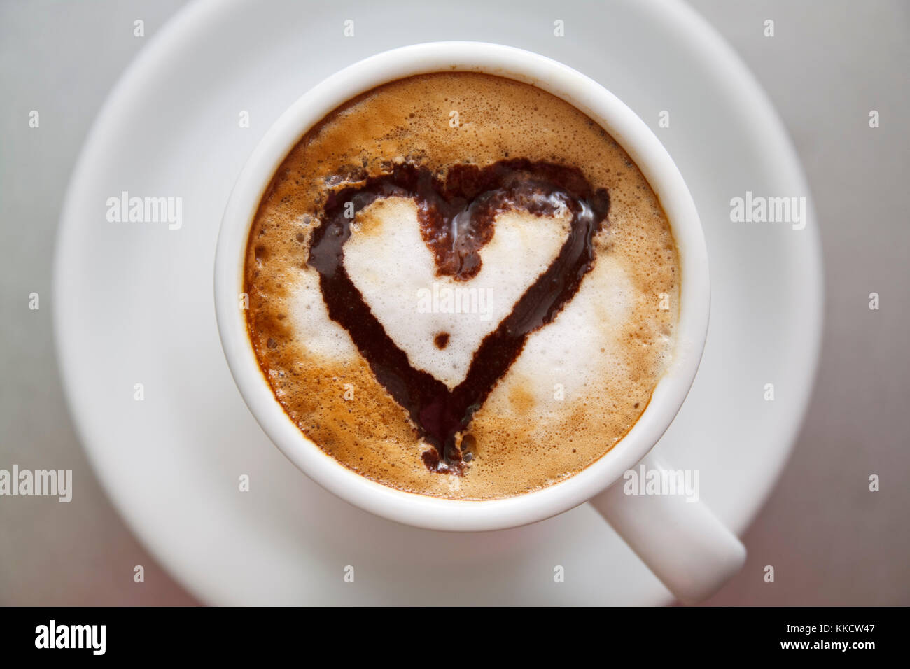 Cup of coffee with a shape of heart made with liquid chocolate on top ...