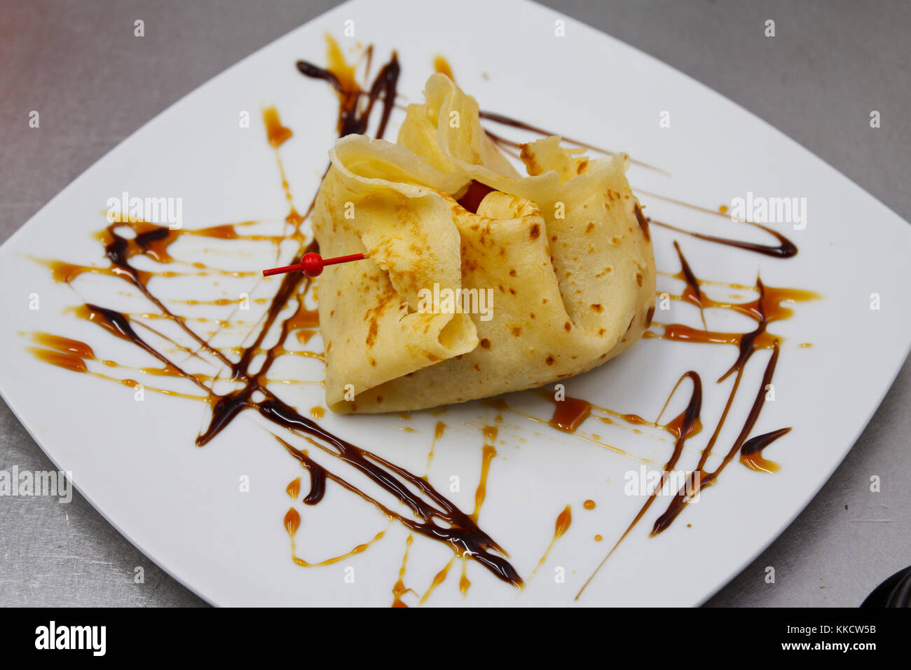 Elegant plate with crepes decorated with syrup Stock Photo - Alamy