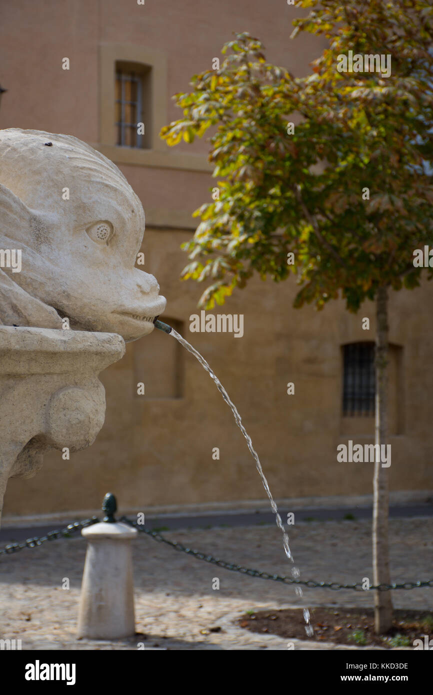 Close up of a carved stylized fish fountain in profile with a stream of ...