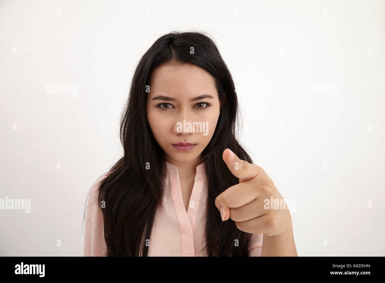 Portrait of a young angry woman pointing finger at camera isolated on a ...