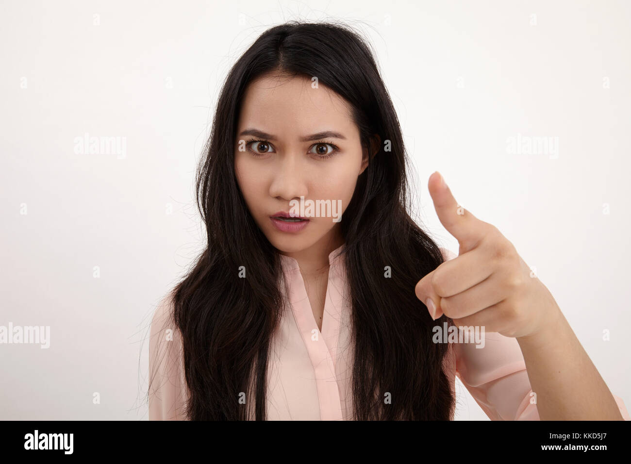 Portrait of a young angry woman pointing finger at camera isolated on a ...